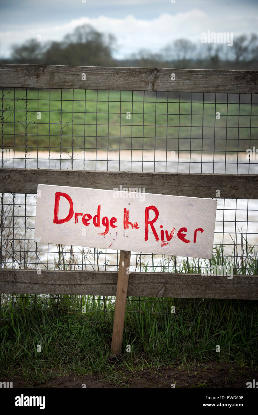 A 'Dredge the River' sign next to a pump outlet draining the flooded ...