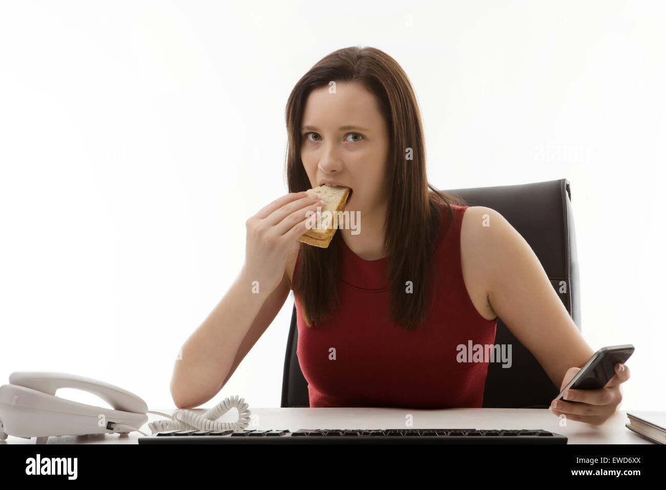 woman sitting at her desk in the office eating a sandwich as well as ...