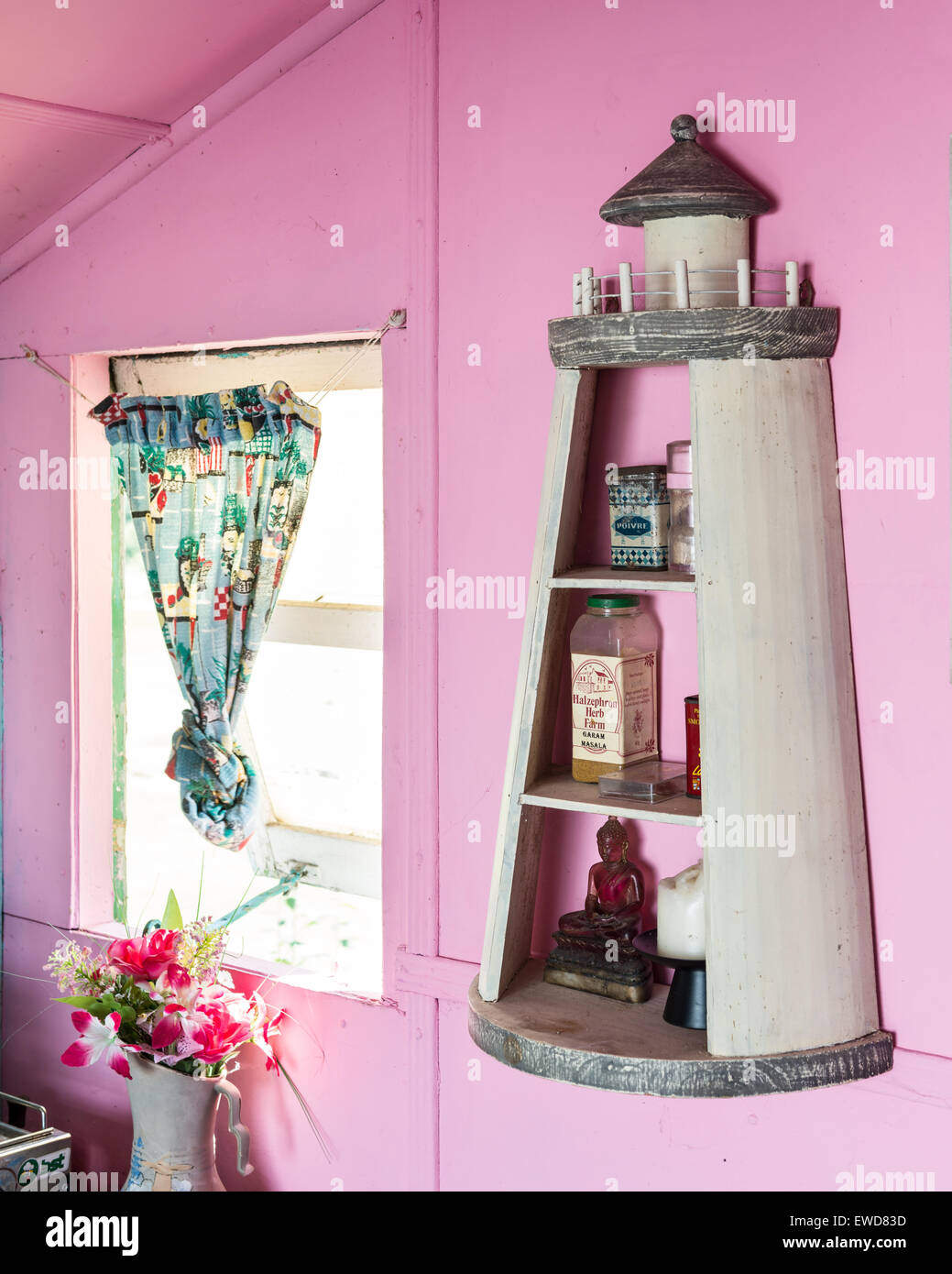 Lighthouse shaped shelf on pink wall of beach hut with vintage curtain ...