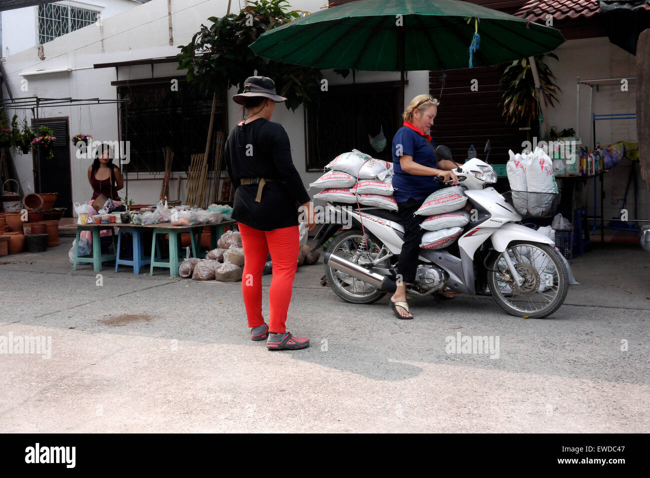Female riding her overloaded motorcycle after a trip to the local ...