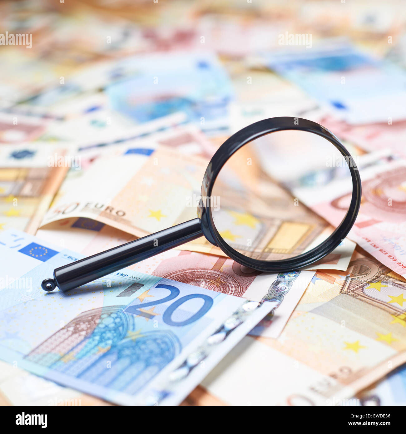 Magnifying glass over the pile of money Stock Photo - Alamy