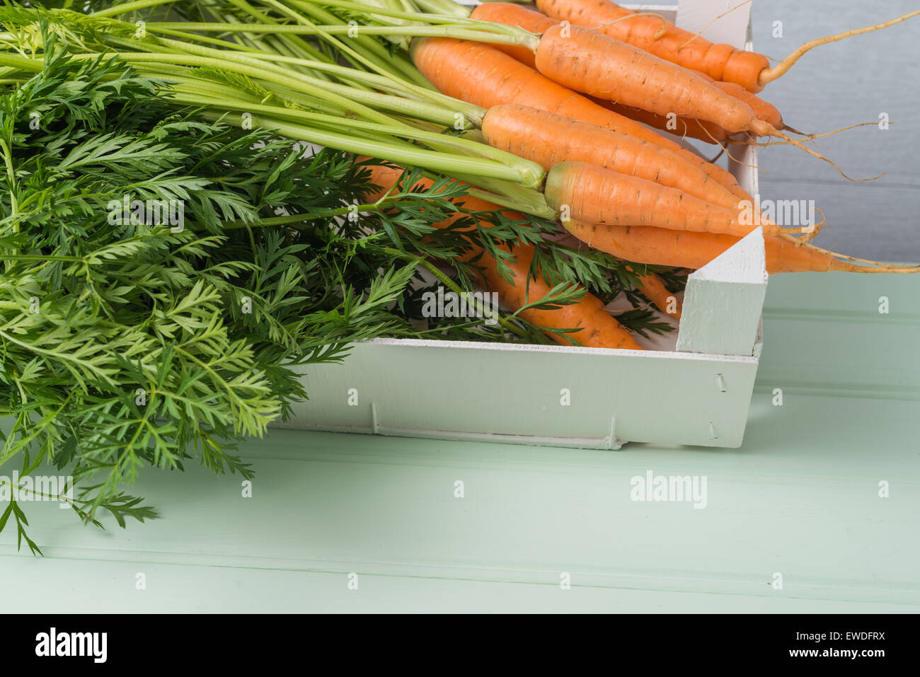 Carrots inside white wooden box on the light green wooden table Stock ...