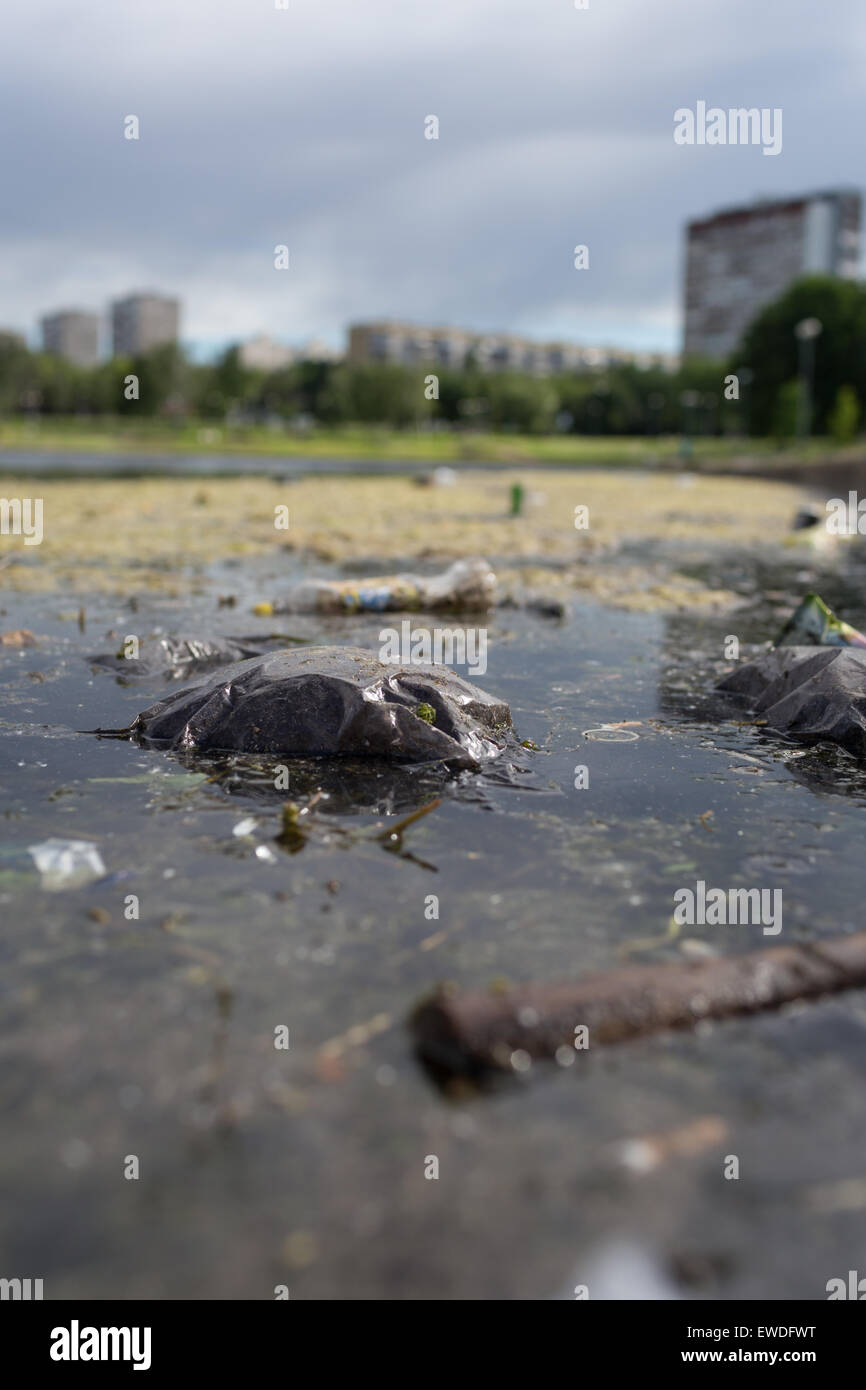 Garbage floating on a lake in a park, surrounded by apartment buildings ...