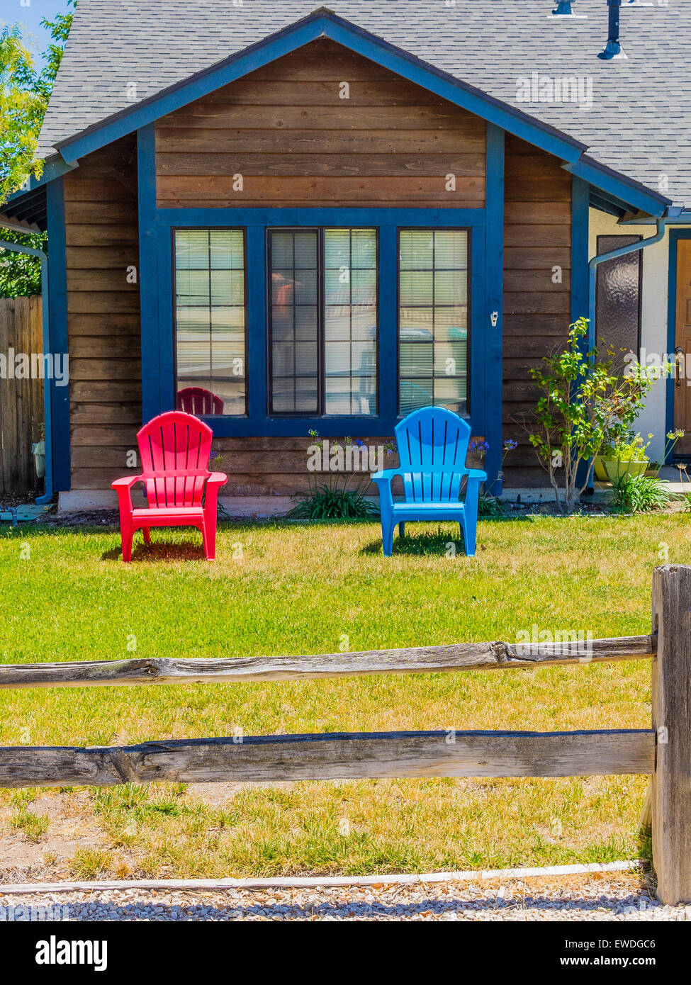 Two brightly colored lawn chairs, one red and the other blue, stand on ...
