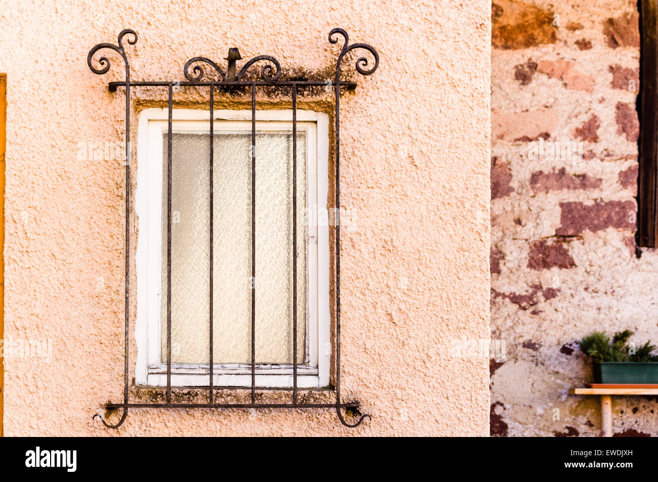 Squared yellow glass window with rusty brown iron grate with stylized ...