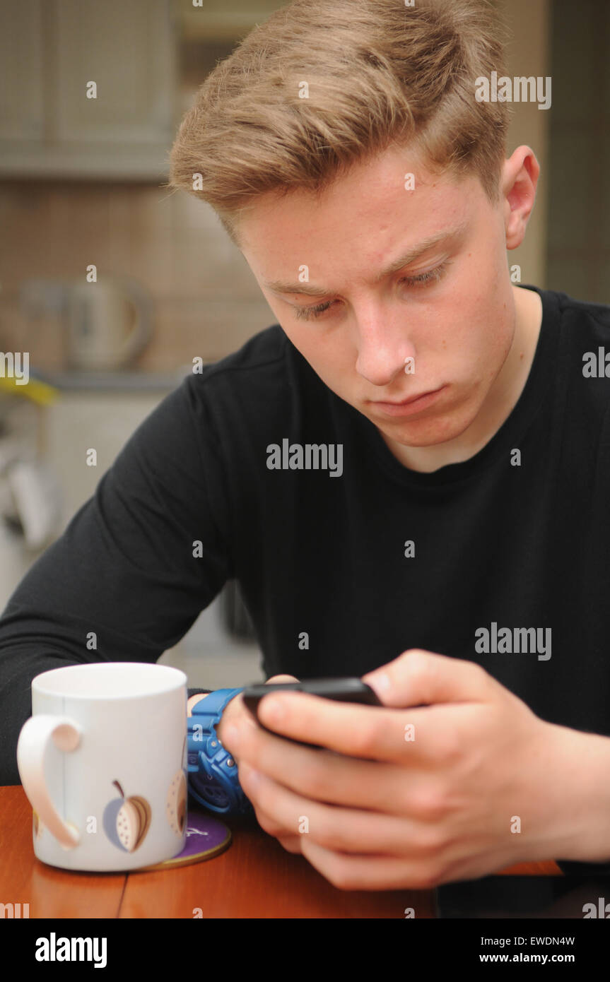 Teenage boy drinking coffee whilst checking his mobile phone Stock ...