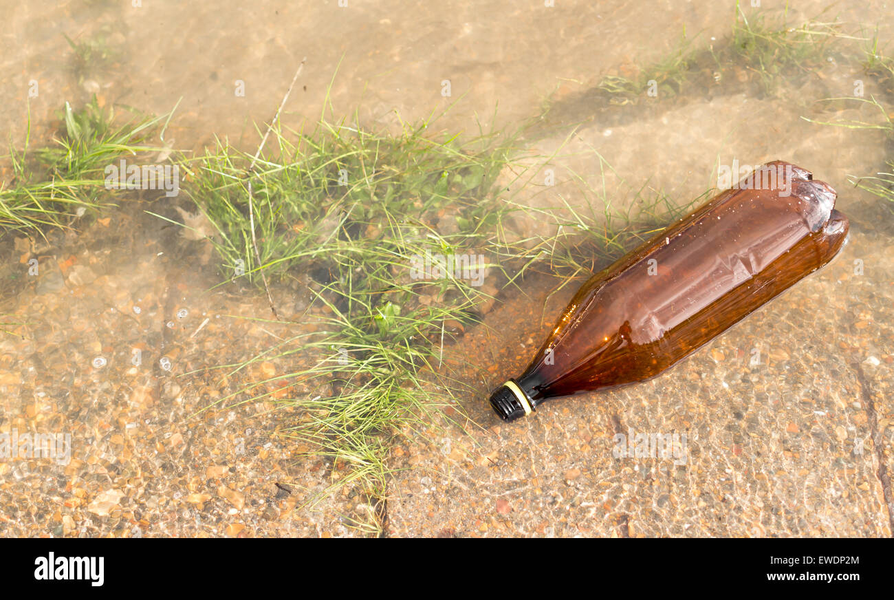 Single brown plastic bottle caught up in the edge of a river Stock ...