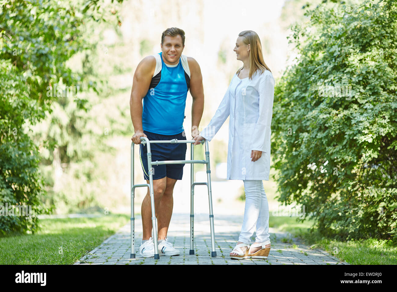 Female clinician and young man with walker taking walk in park Stock ...