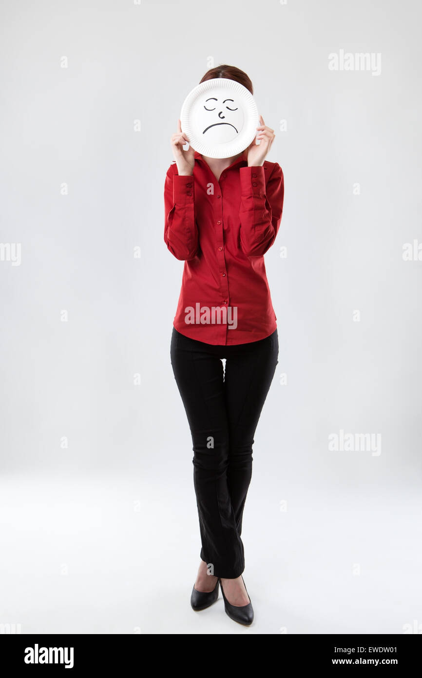 business woman with a paper plate up to her face with a sad face drawn ...