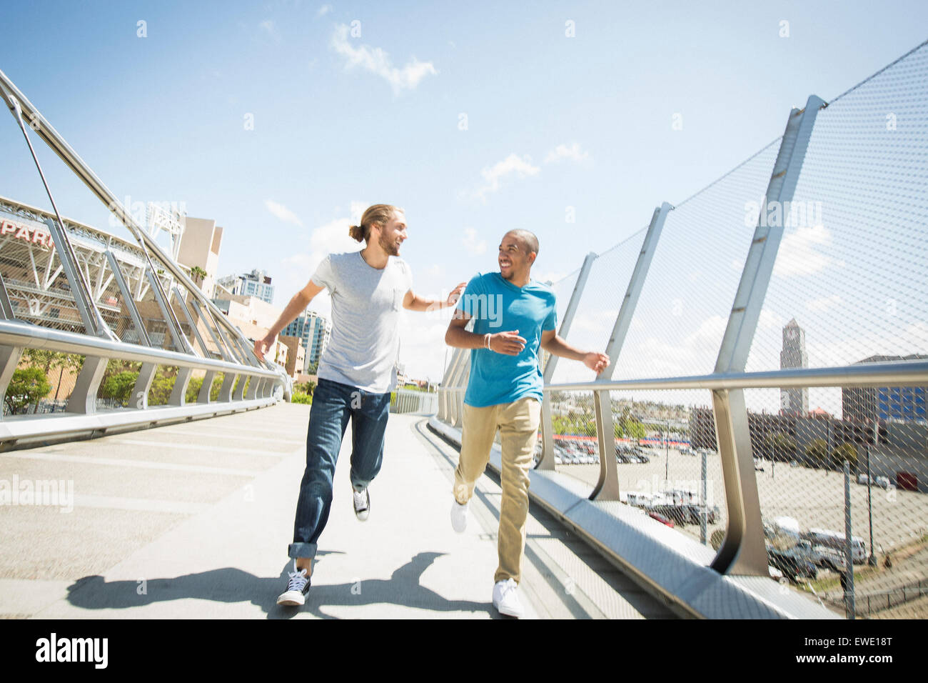 Two young men jogging along footbridge Stock Photo - Alamy