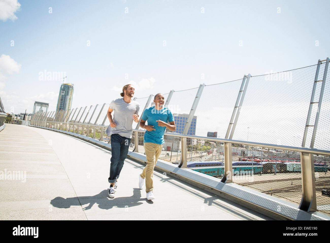 Two young men jogging along footbridge Stock Photo - Alamy