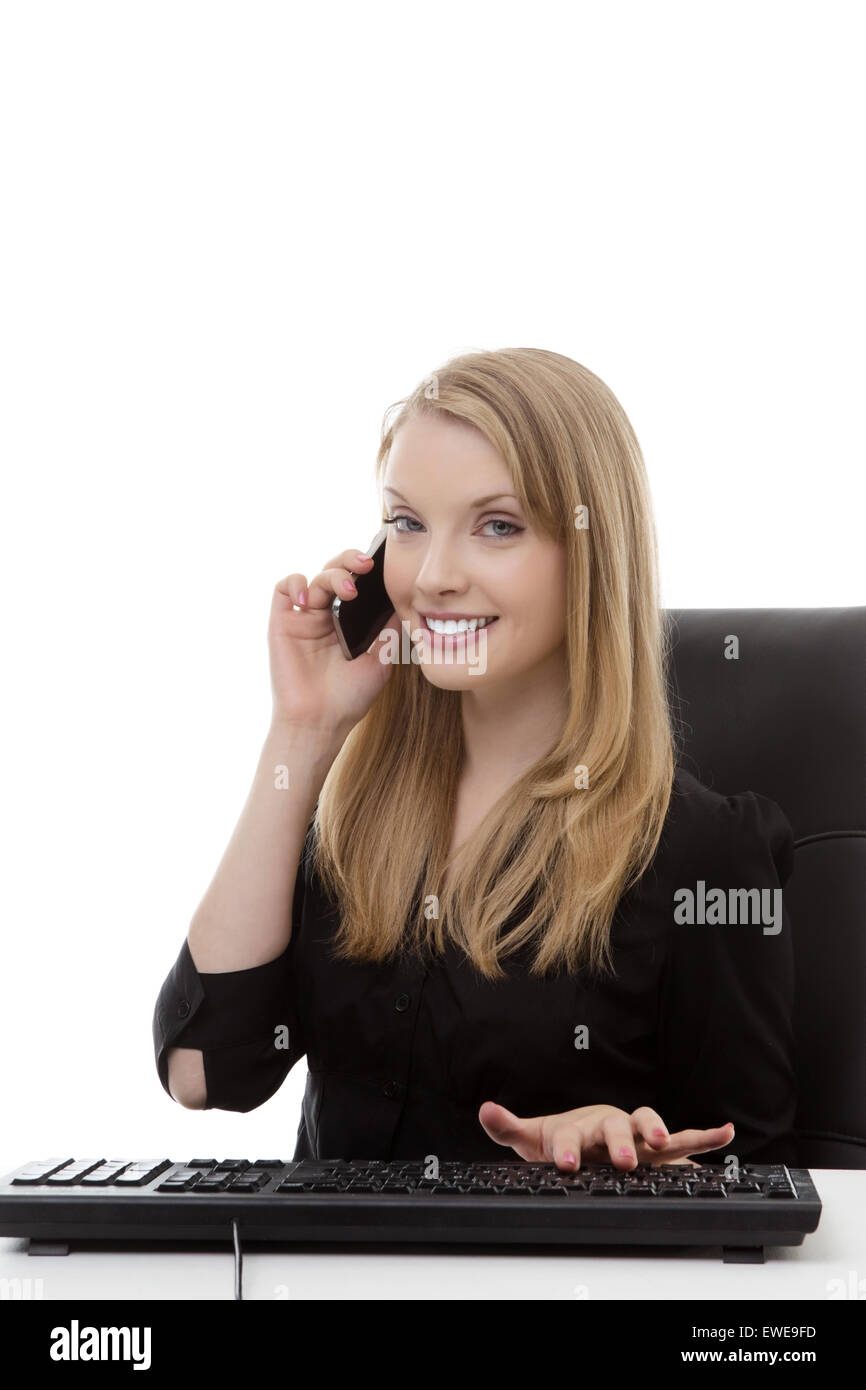woman typing away on her keyboard hard at work and answering a mobile ...