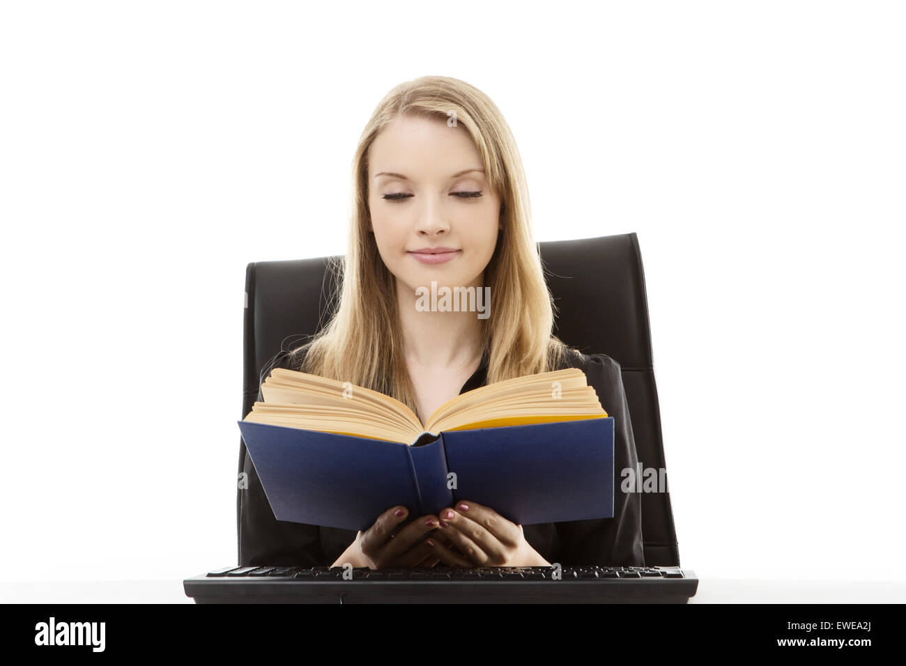 woman at work sitting at her desk reading a book Stock Photo - Alamy