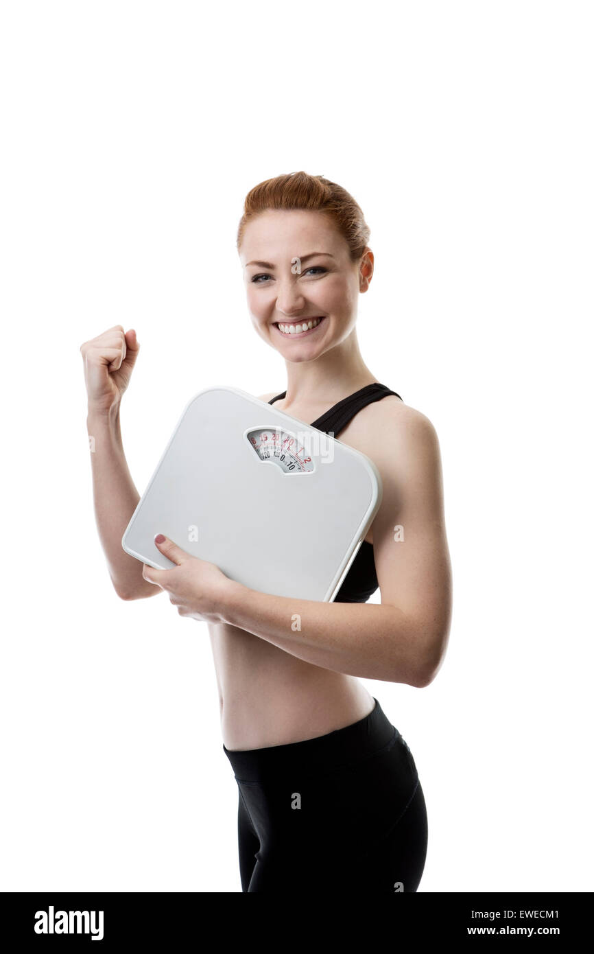 happy woman holding scales with her arm up for joy after reaching her ...