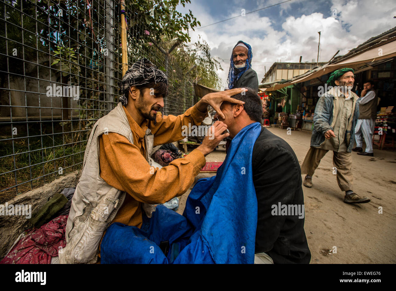 Barber shaves client on Bazaar street in Old city of Kabul, Afghanistan ...