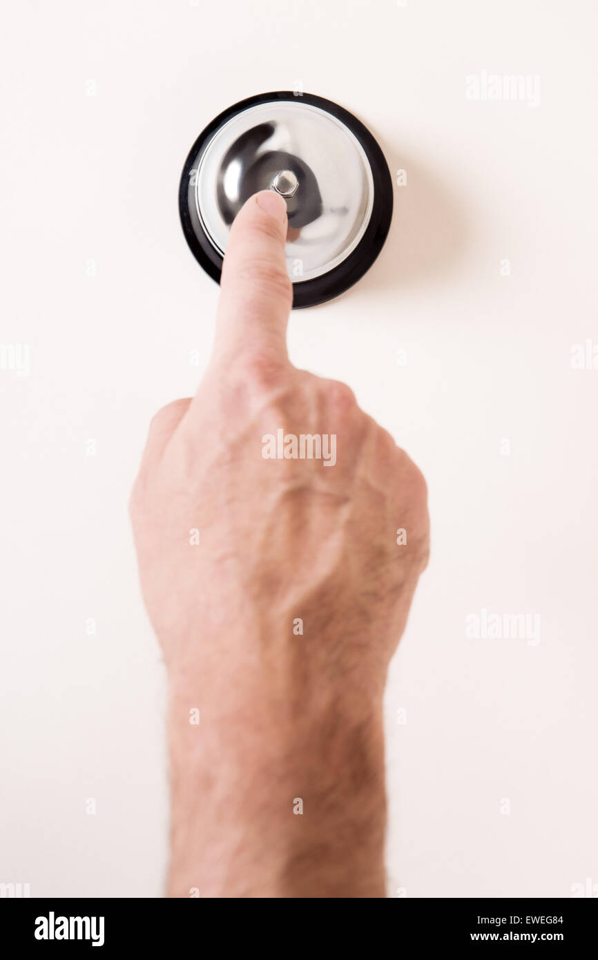 Shot from above of a man's hand pressing a service bell shot on a white ...