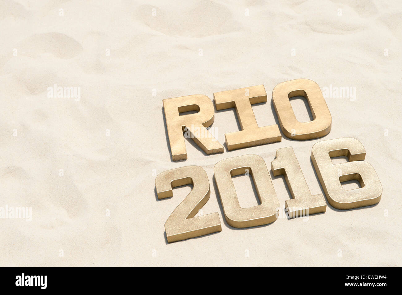 Golden Rio 2016 sign sitting on smooth sand beach background in Rio de ...