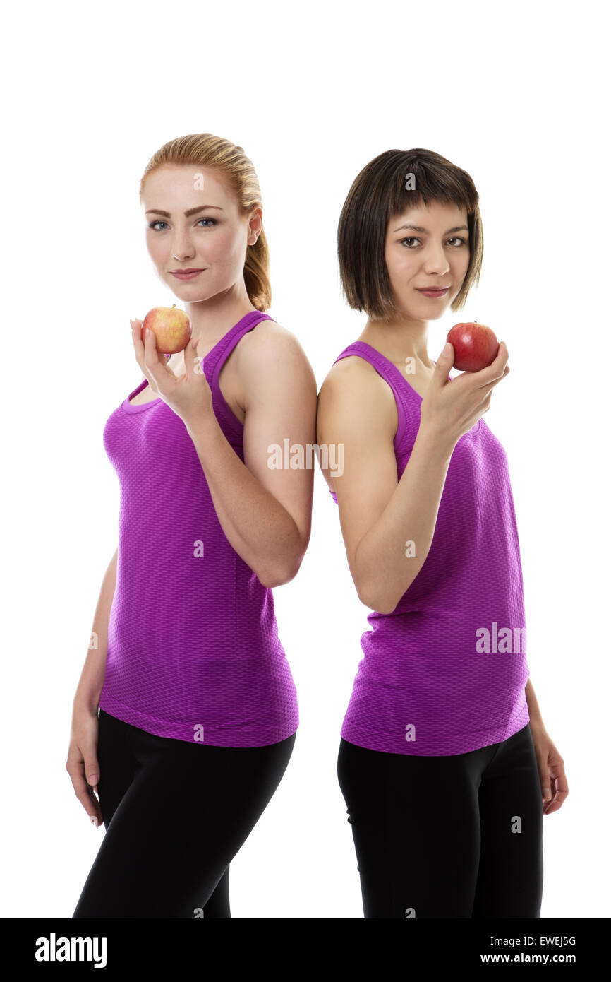 two fitness models standing back to back holding an apple Stock Photo ...