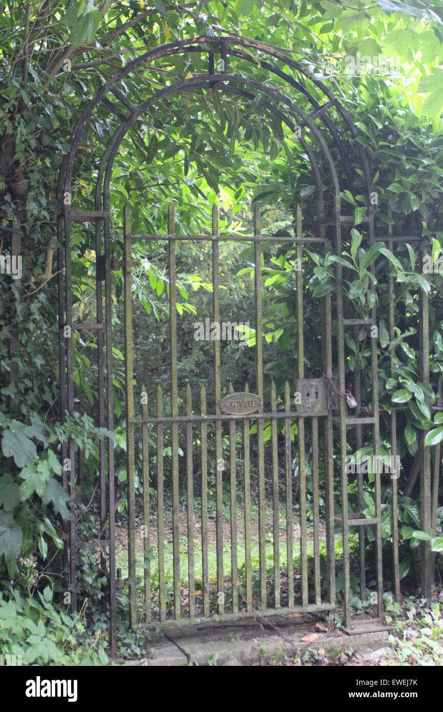 A wrought iron gate locked with private on the front, old and rusting ...
