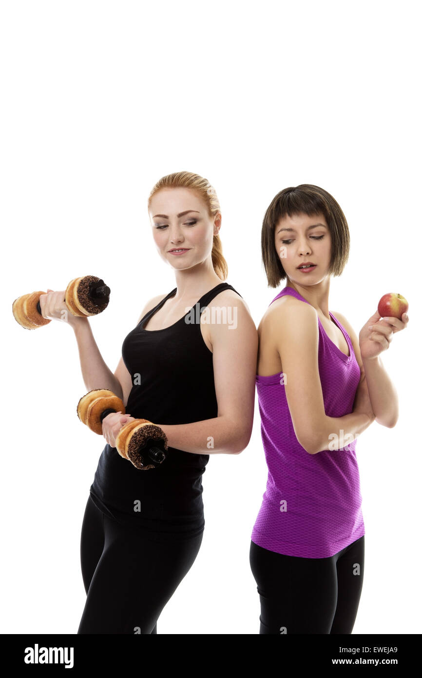 two fitness model standing back to back one is eatting an apple and the ...