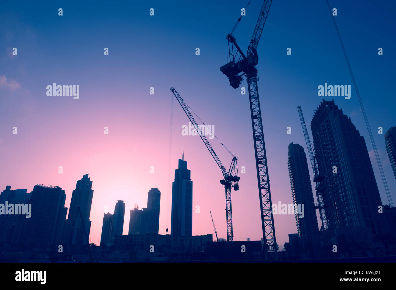Sunset skyline of construction cranes amongst office tower skyscrapers ...