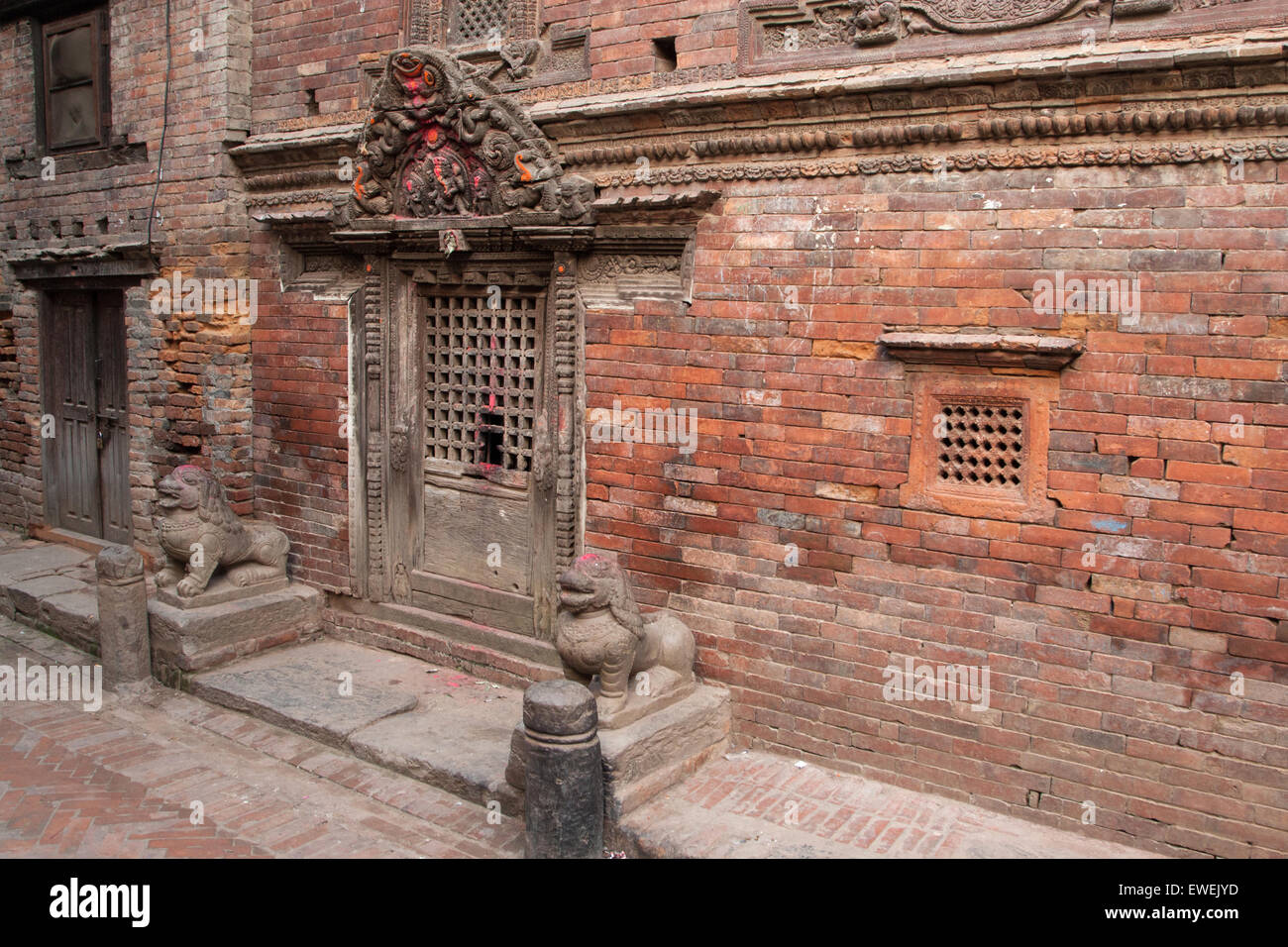 A brick house in Bhaktapur, Nepal, with stone lions and a god figure ...