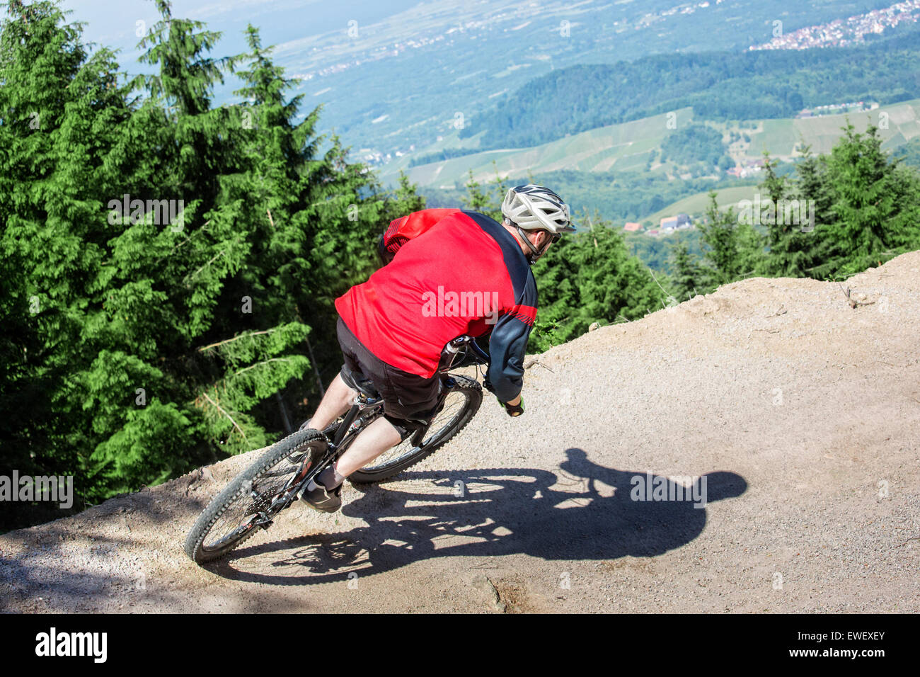 Mountain bike rider rides through a gravity slope of an artificial dirt ...