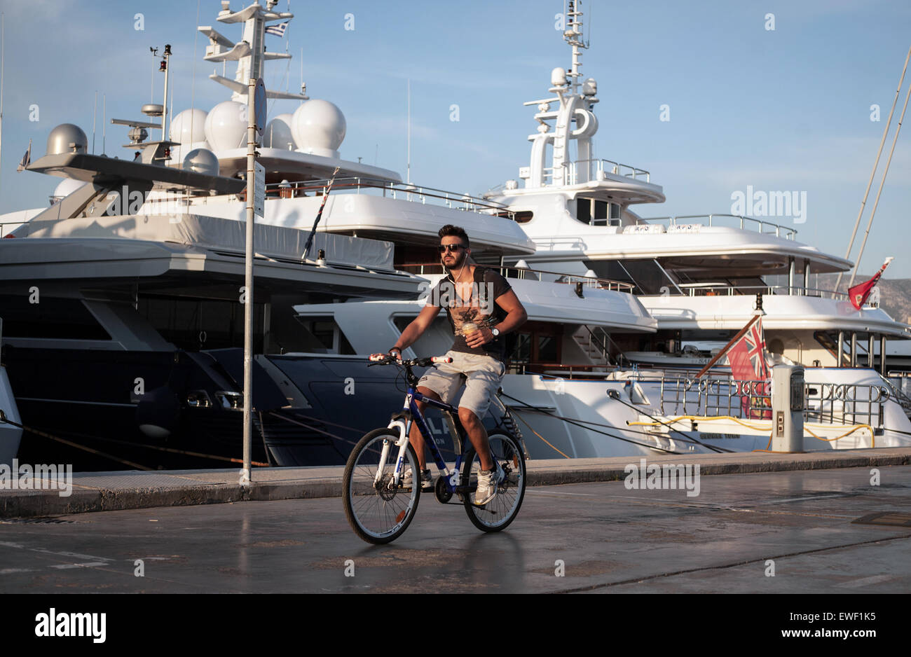 A man is riding his bicycle among yachts at a marina in Athens, Greece ...