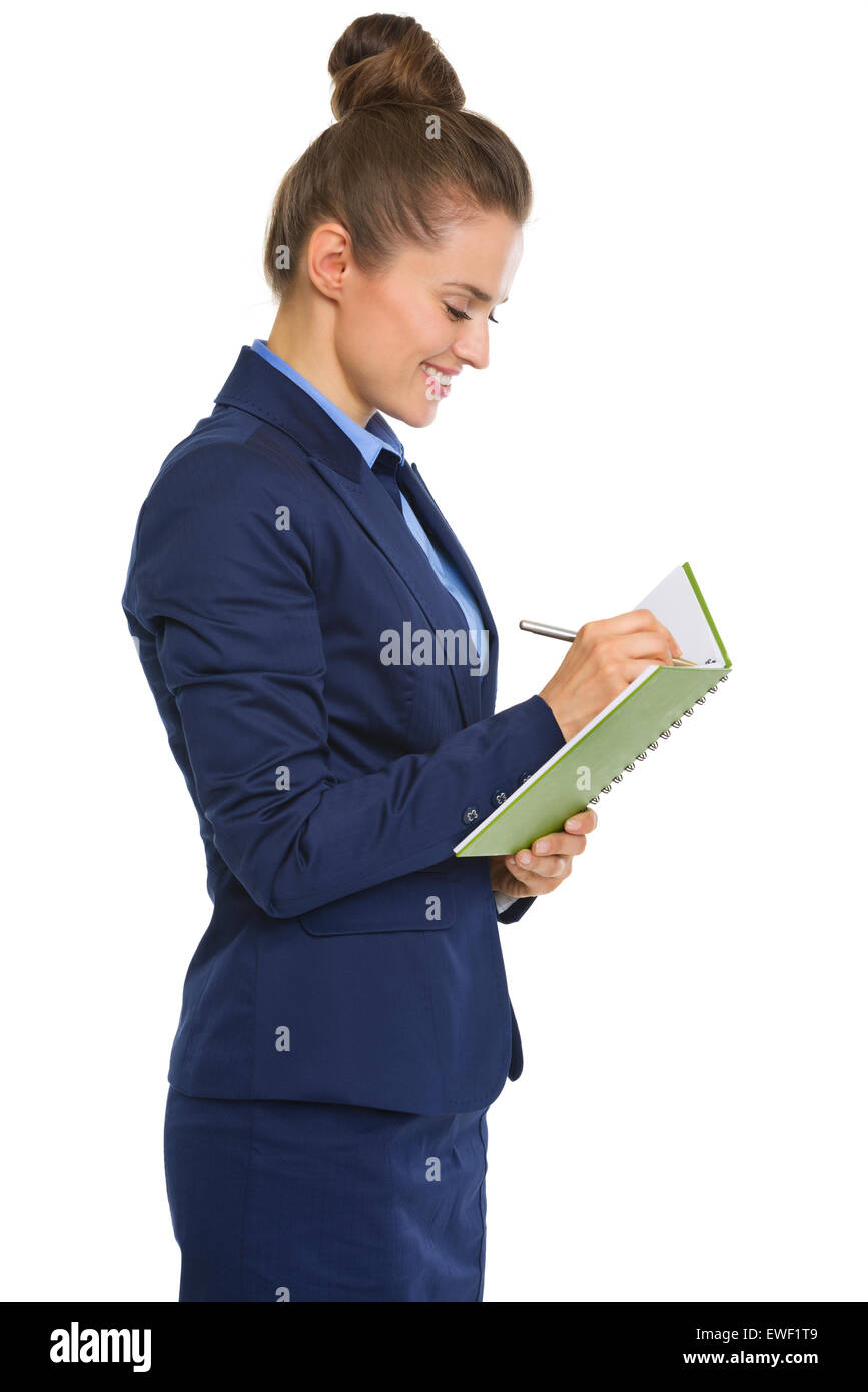 Taking notes while listening, an elegant businesswoman looks down while ...