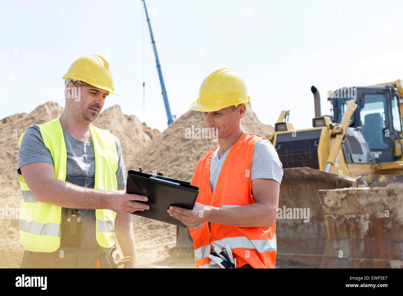 Engineers reading clipboard at construction site against clear sky ...