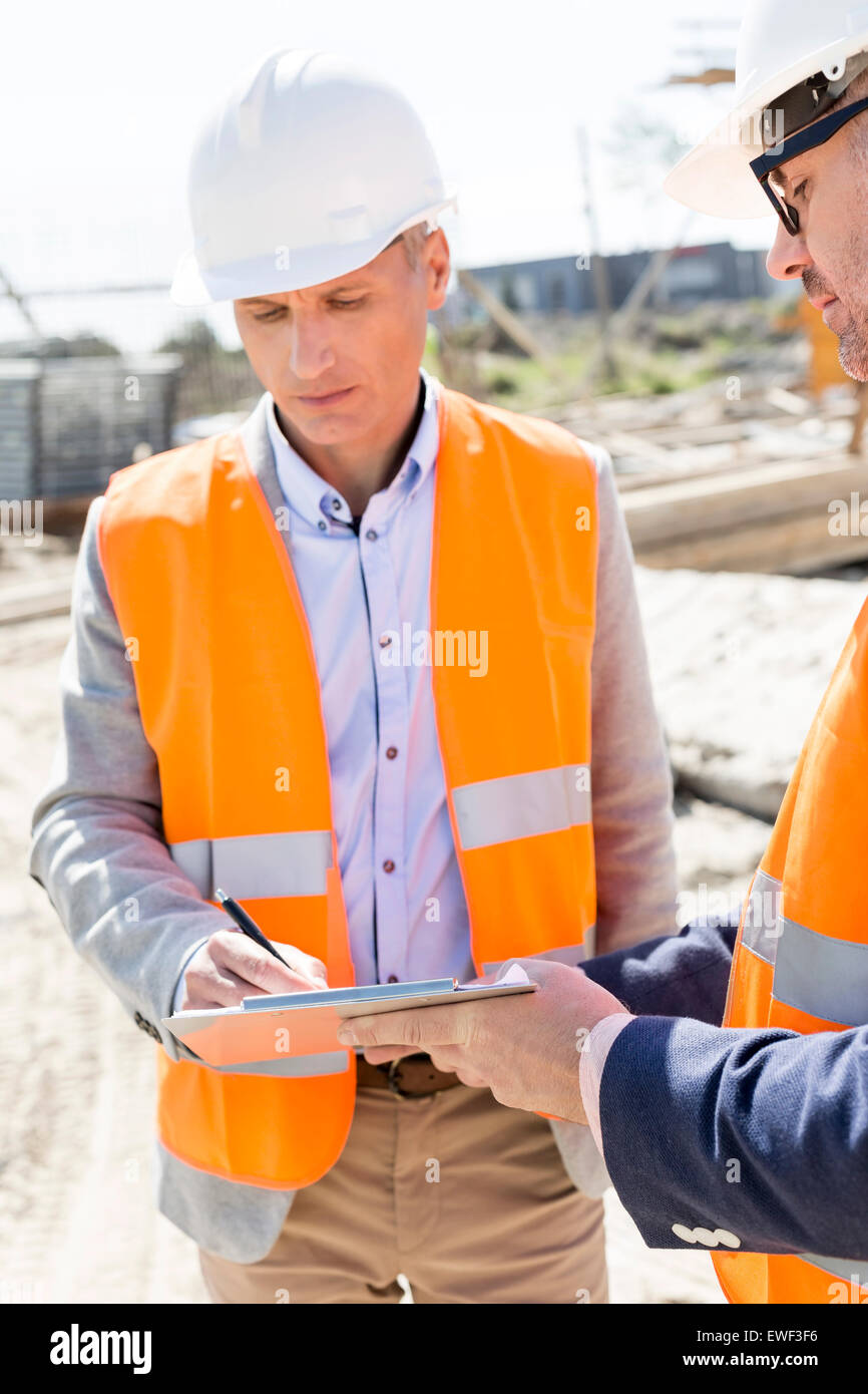 Engineers writing on clipboard at construction site Stock Photo - Alamy