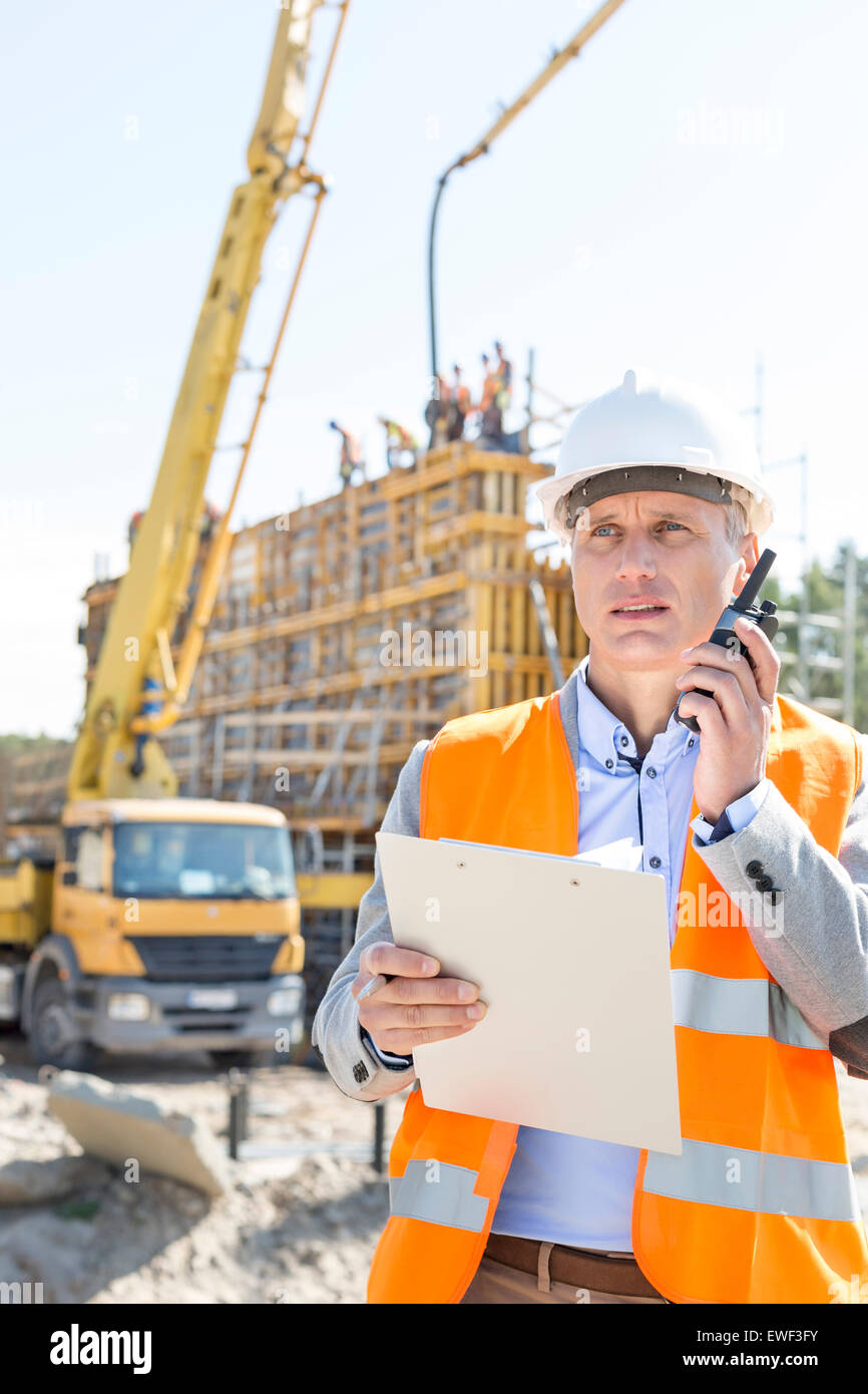 Supervisor using walkie talkie holding clipboard hi-res stock ...