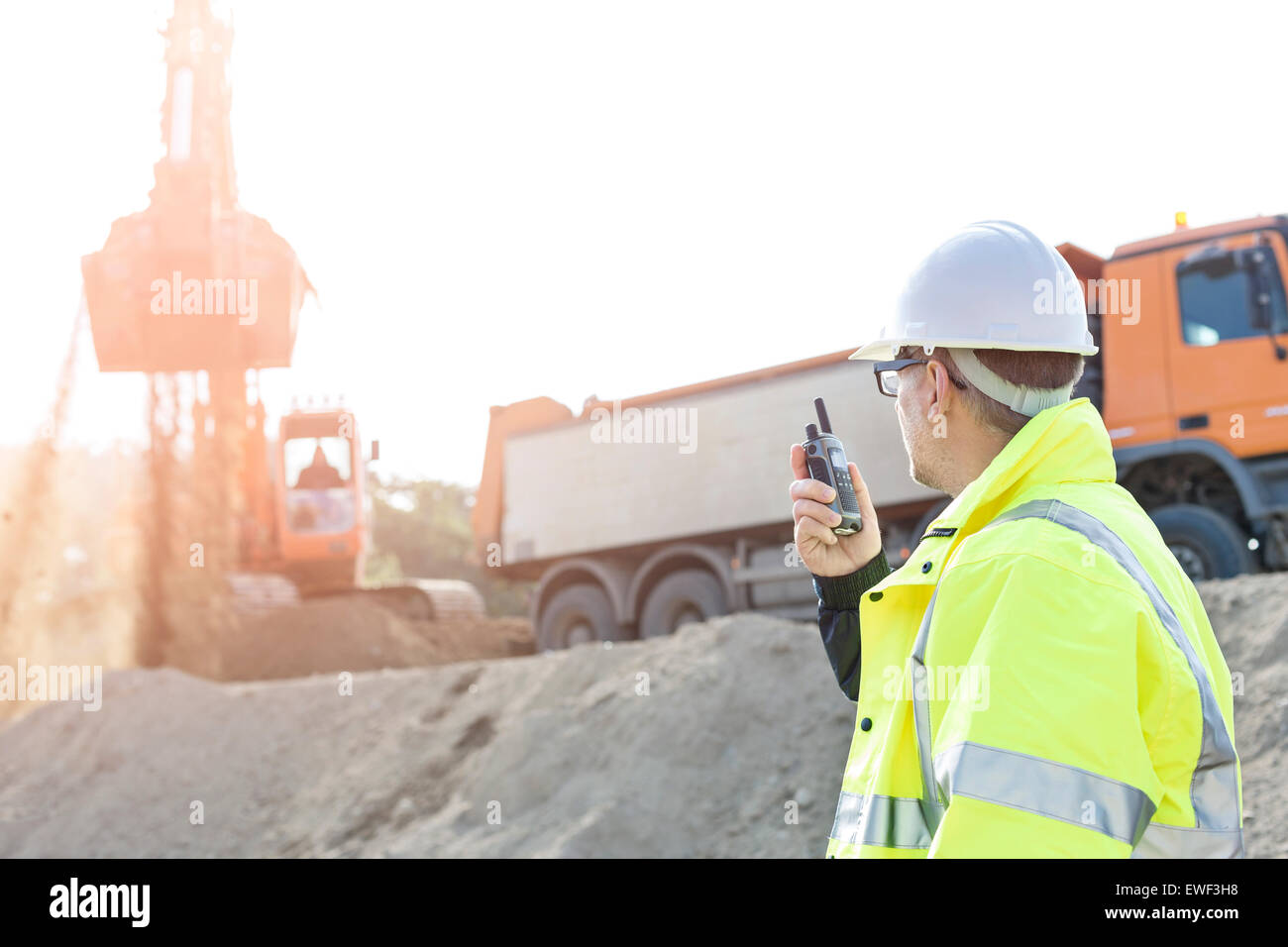 Side view of supervisor using walkie-talkie at construction site ...