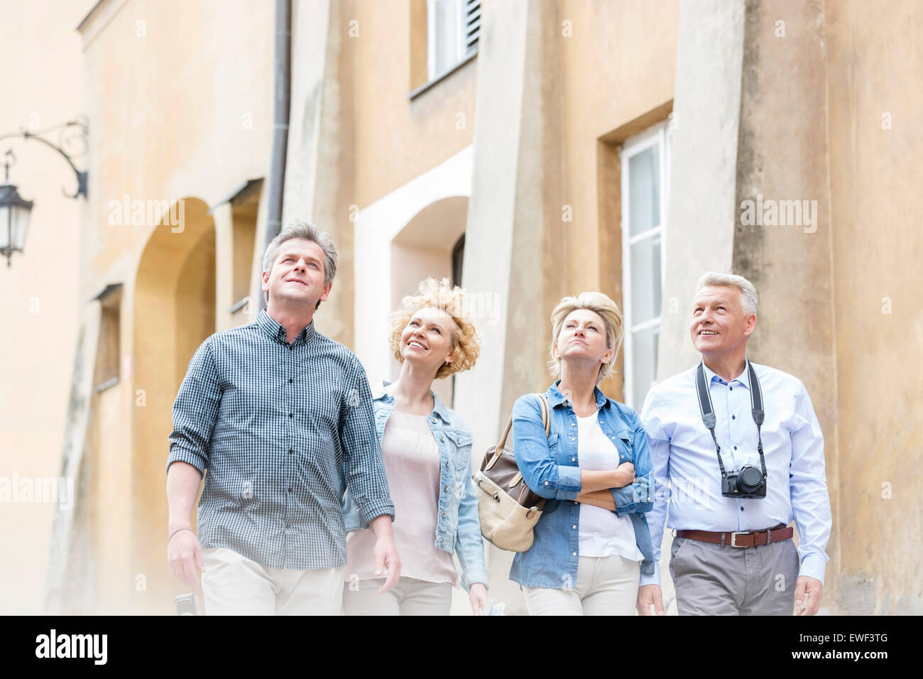 Smiling friends looking up while walking by building Stock Photo - Alamy