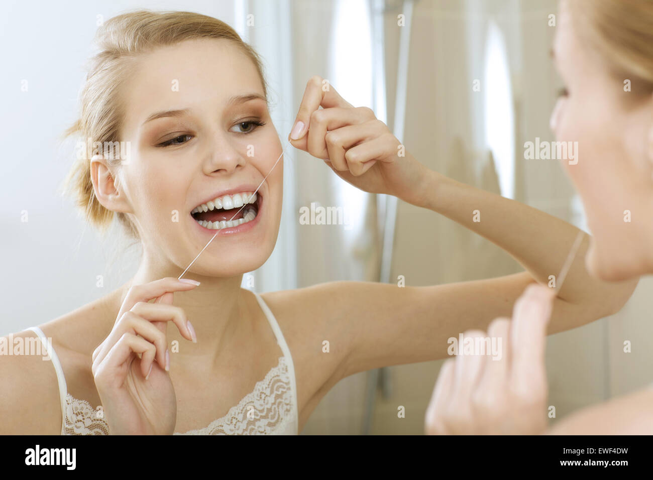 A young woman flossing her teeth Stock Photo - Alamy