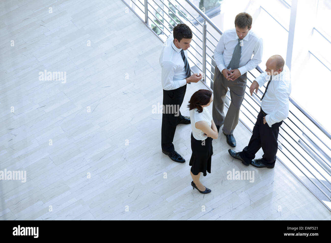 Businessmen and woman standing together by railing and conversing Stock ...