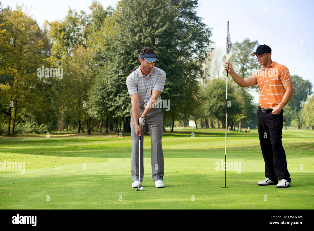 Young man with his friend playing golf in golf course Stock Photo - Alamy