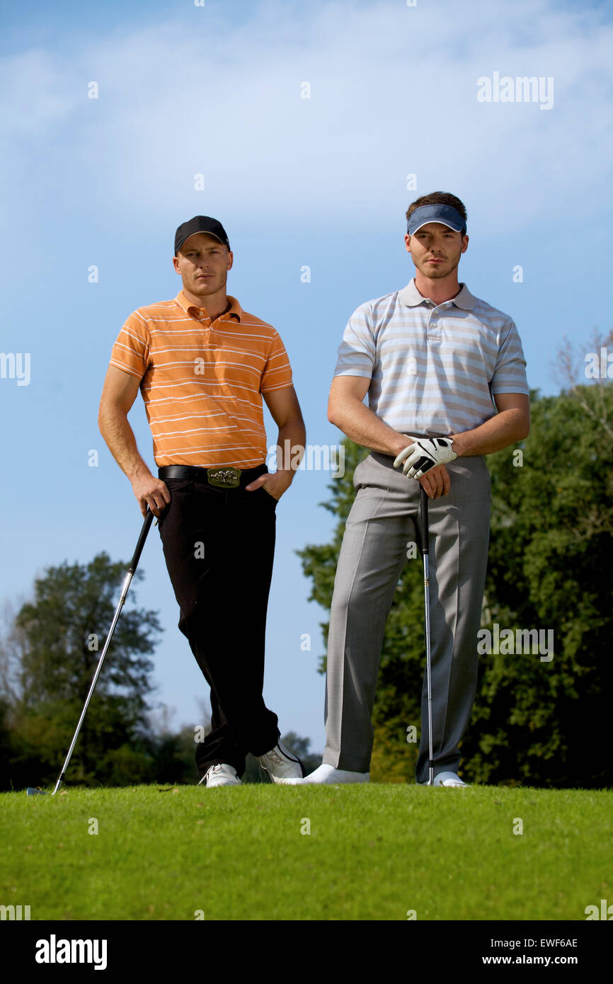 Portrait of young men standing with golf sticks on golf course Stock ...