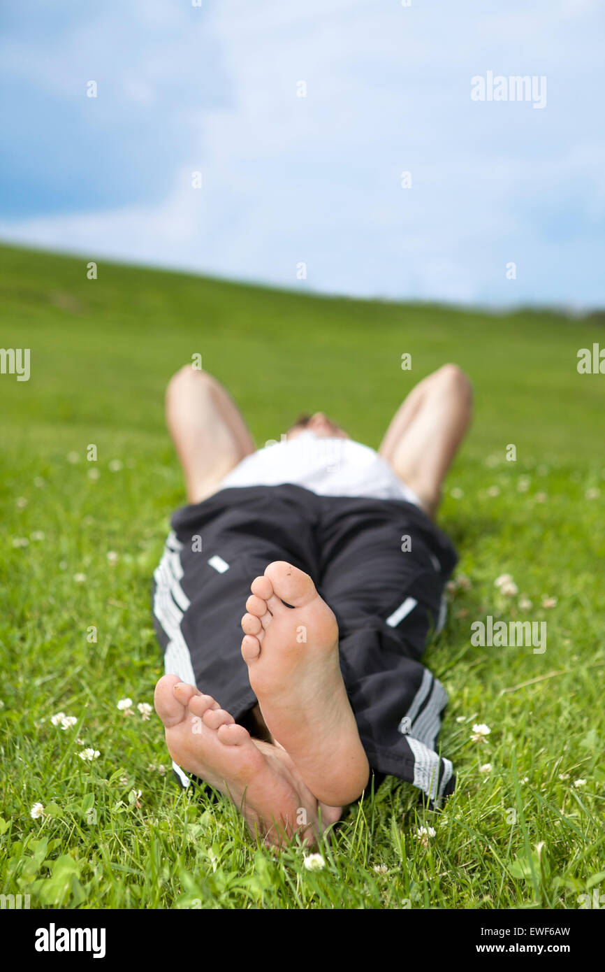 Young man lying on grass in park Stock Photo - Alamy