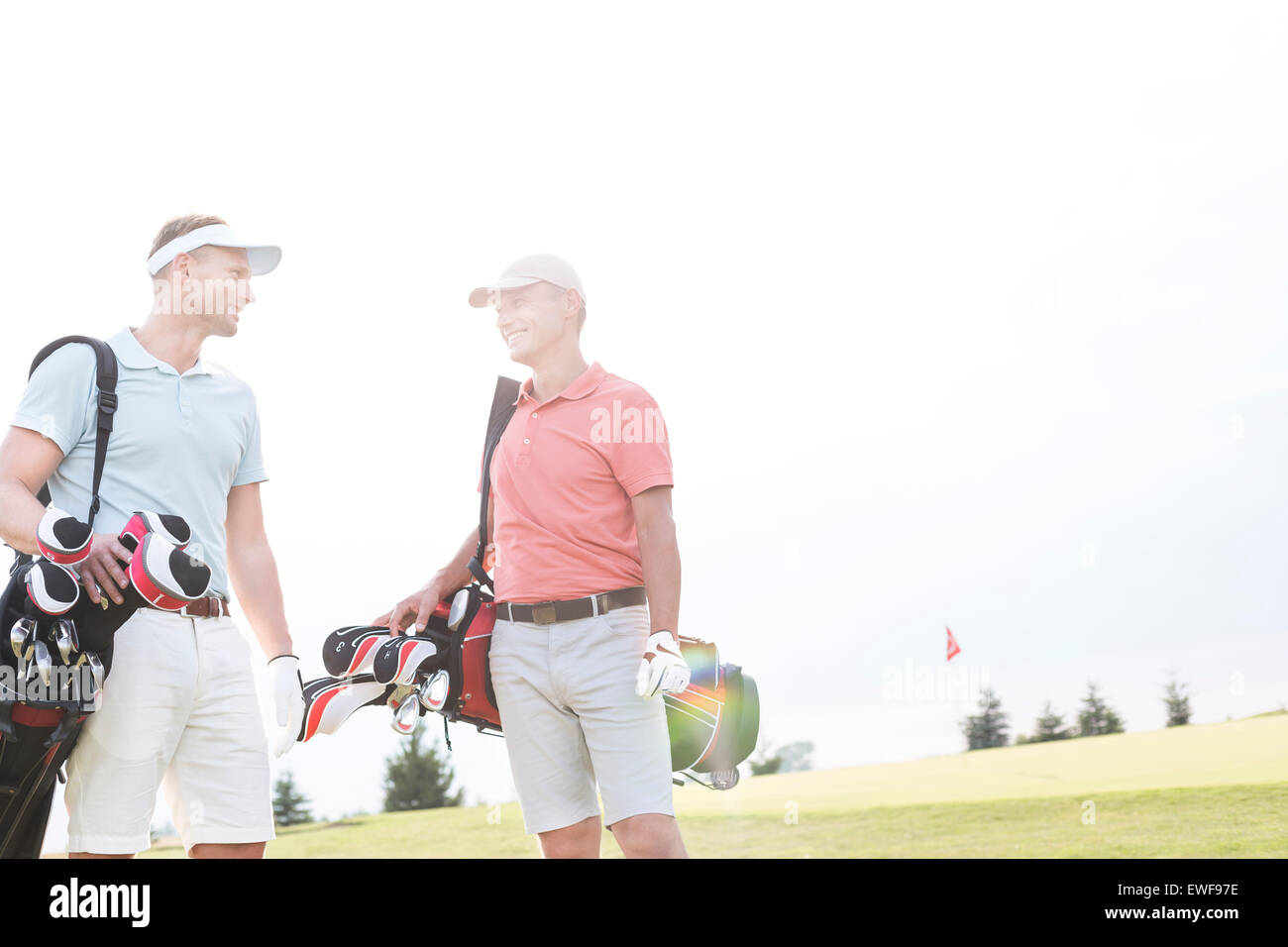 Smiling men talking at golf course against clear sky Stock Photo - Alamy