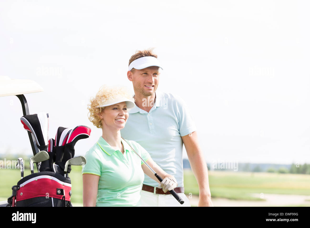 Smiling golfers standing at golf course against clear sky Stock Photo ...