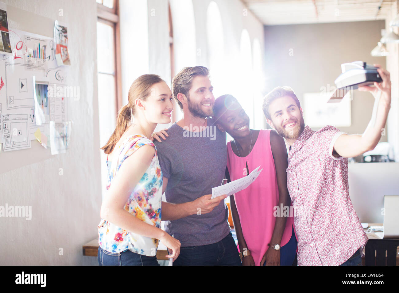 Creative business people taking selfie with instant camera in office ...