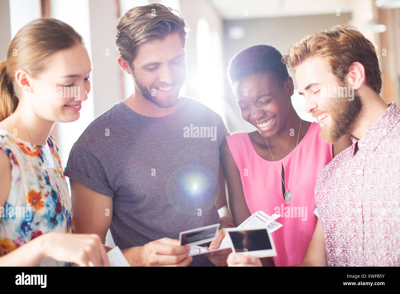Smiling casual business people looking at instant photos Stock Photo ...