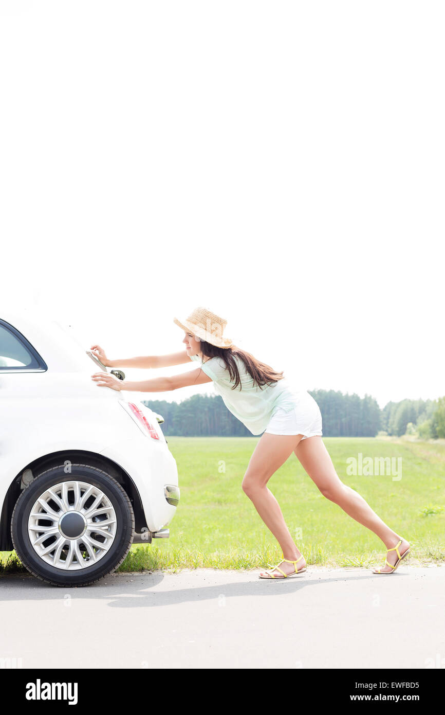 Side view of woman pushing broken down car on country road Stock Photo ...