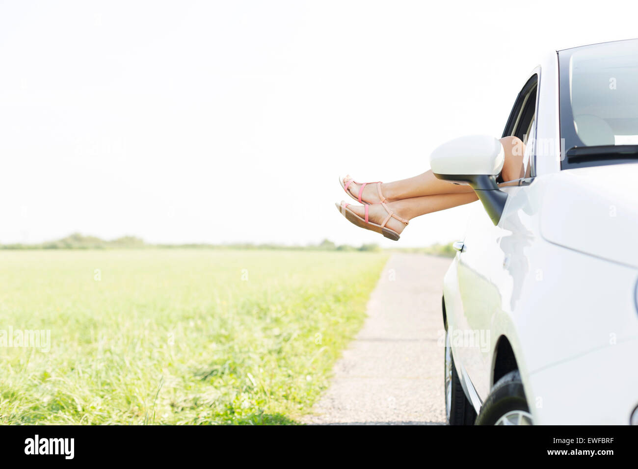 Low section of woman relaxing in car on country road Stock Photo - Alamy