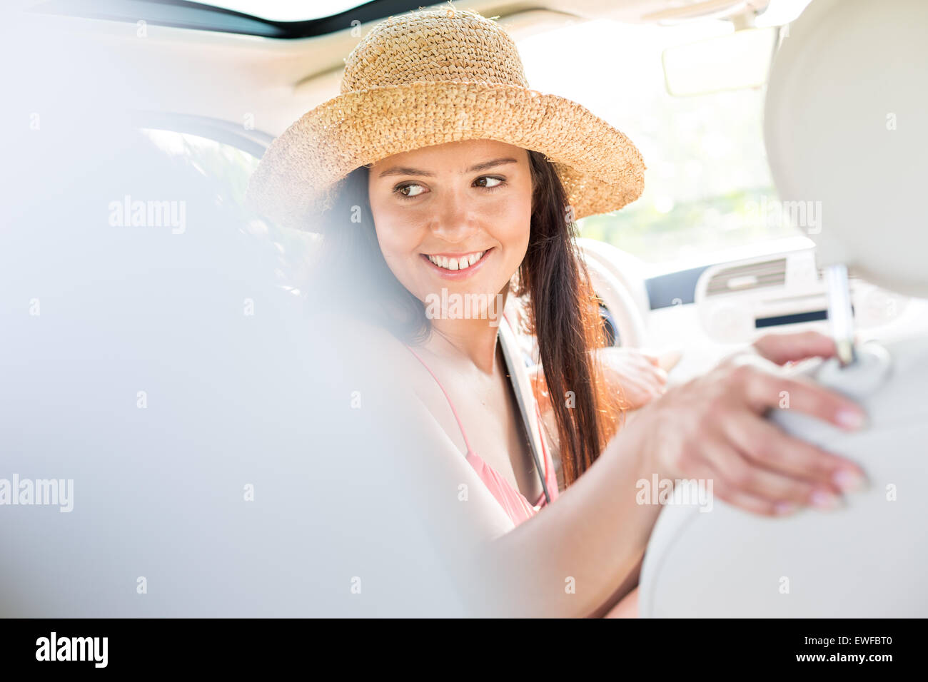 Happy woman looking back while driving car Stock Photo - Alamy