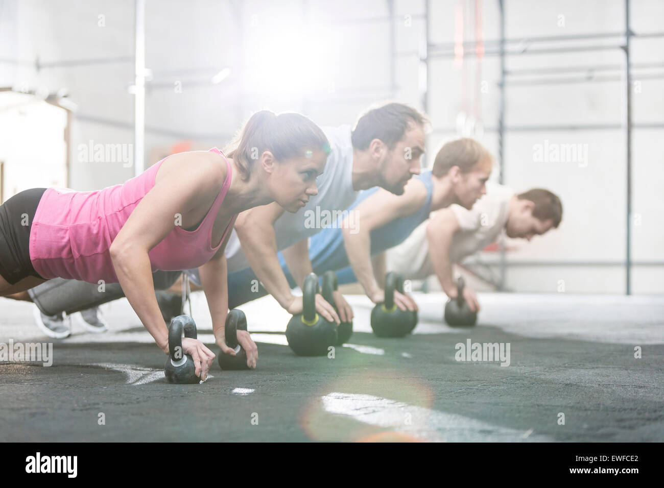 Side view of determined people doing pushups with kettlebells at ...