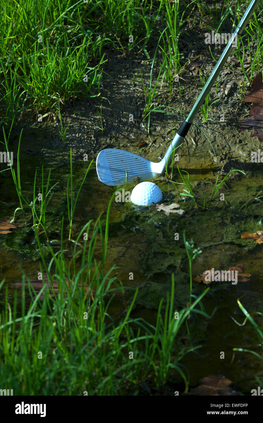 Man chipping ball from water hazard Stock Photo - Alamy