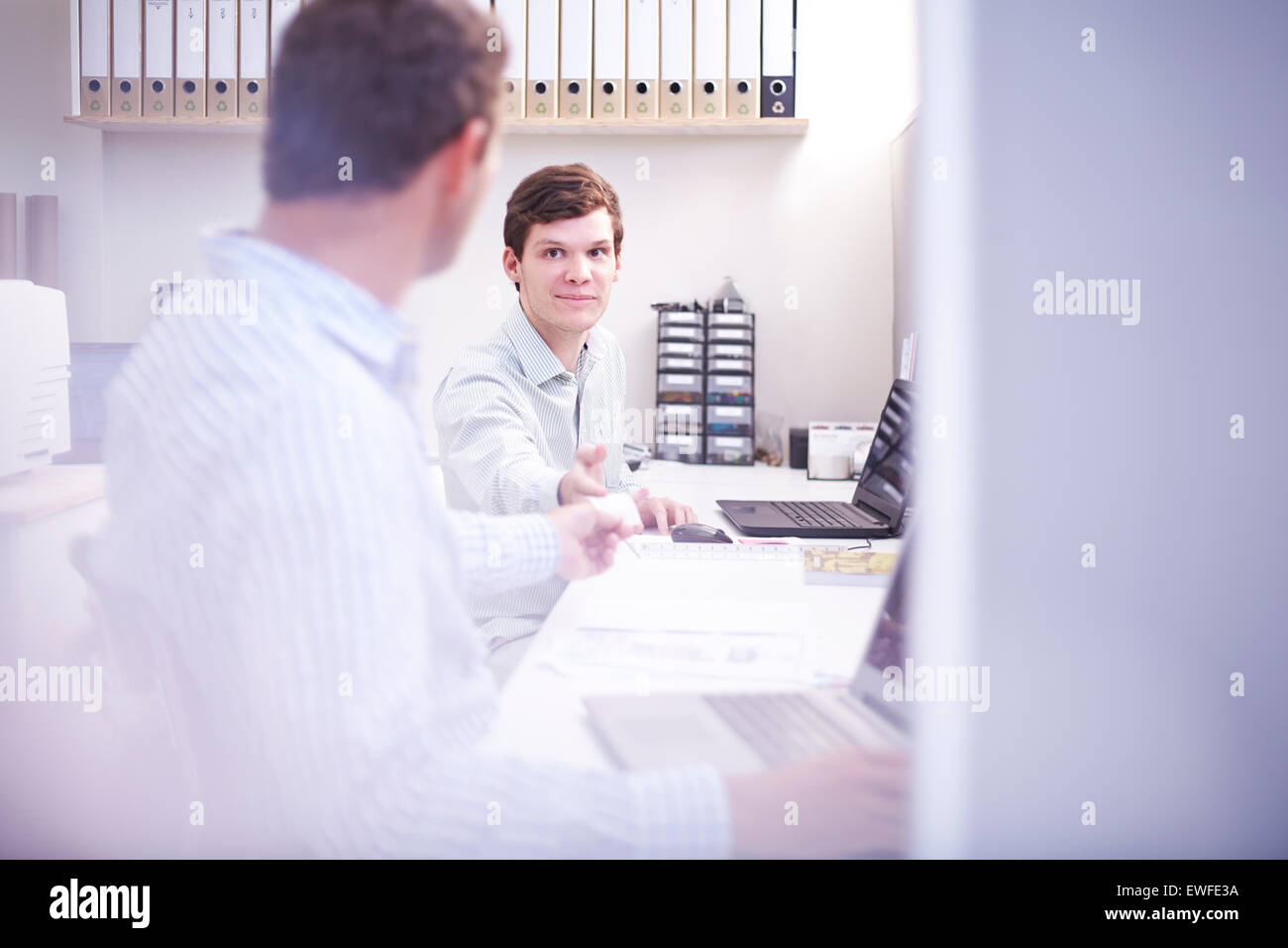 Architects discussing paperwork at desk in office Stock Photo - Alamy