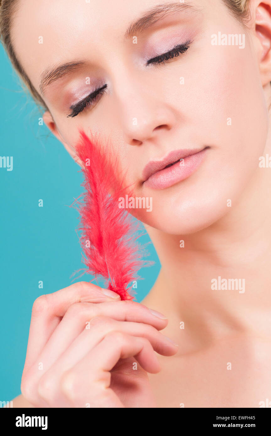 Beautiful young Caucasian woman feeling face with a red feather Stock ...